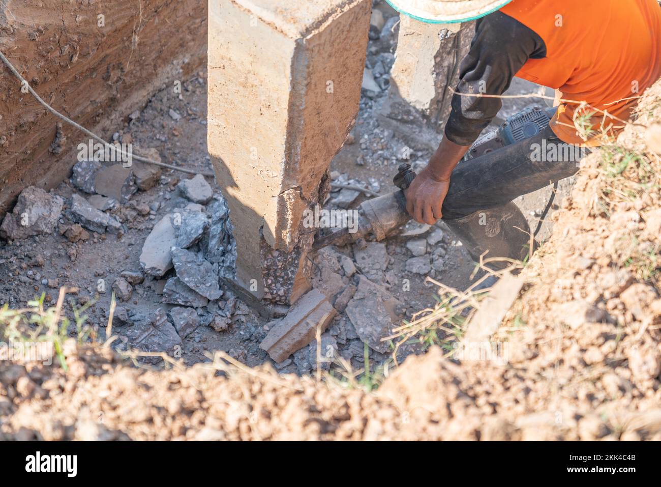 A worker with a jackhammer breaks concrete piles. Preparation of piles ...