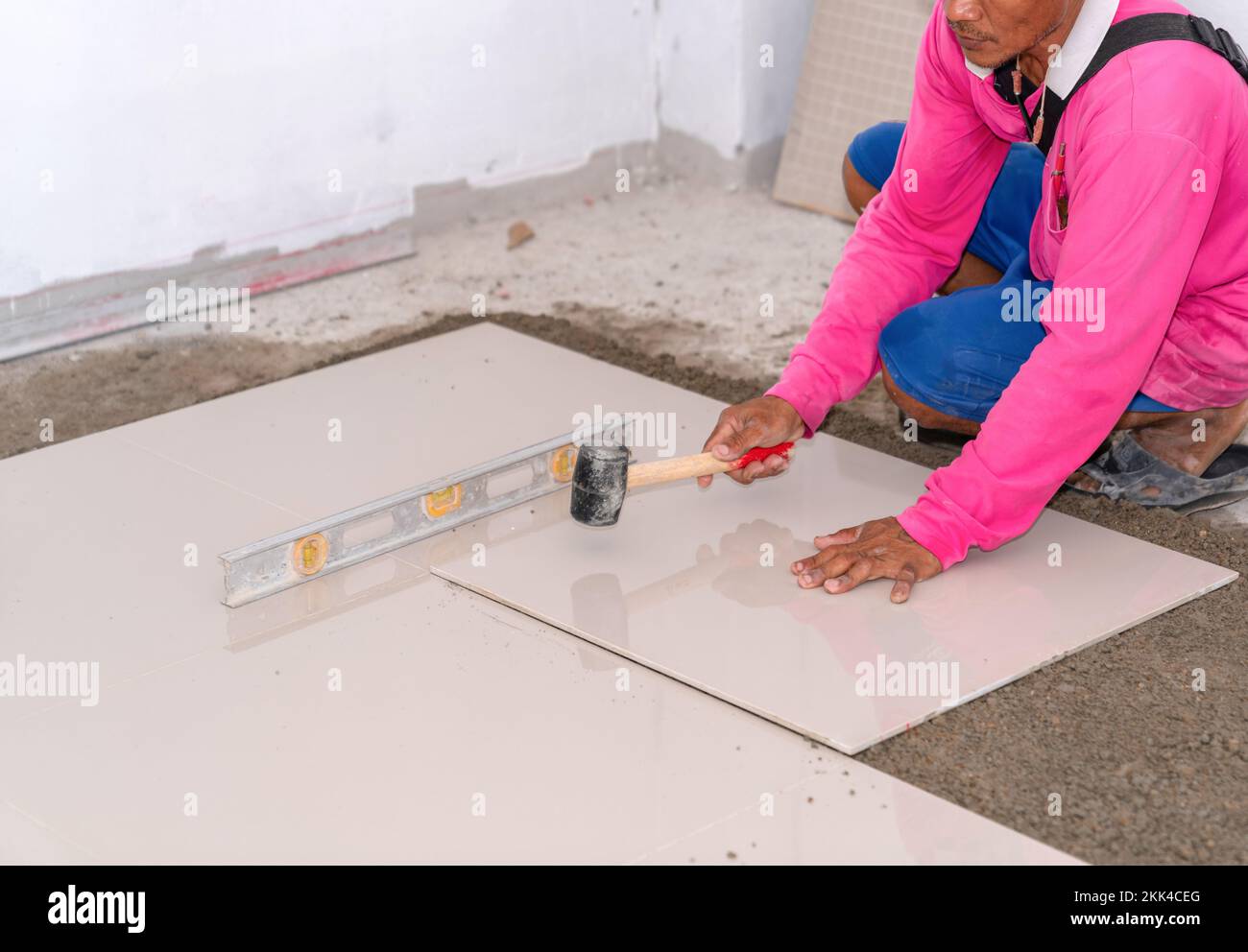 Worker laying the ceramic tile on the floor and knock for smooth floor ...