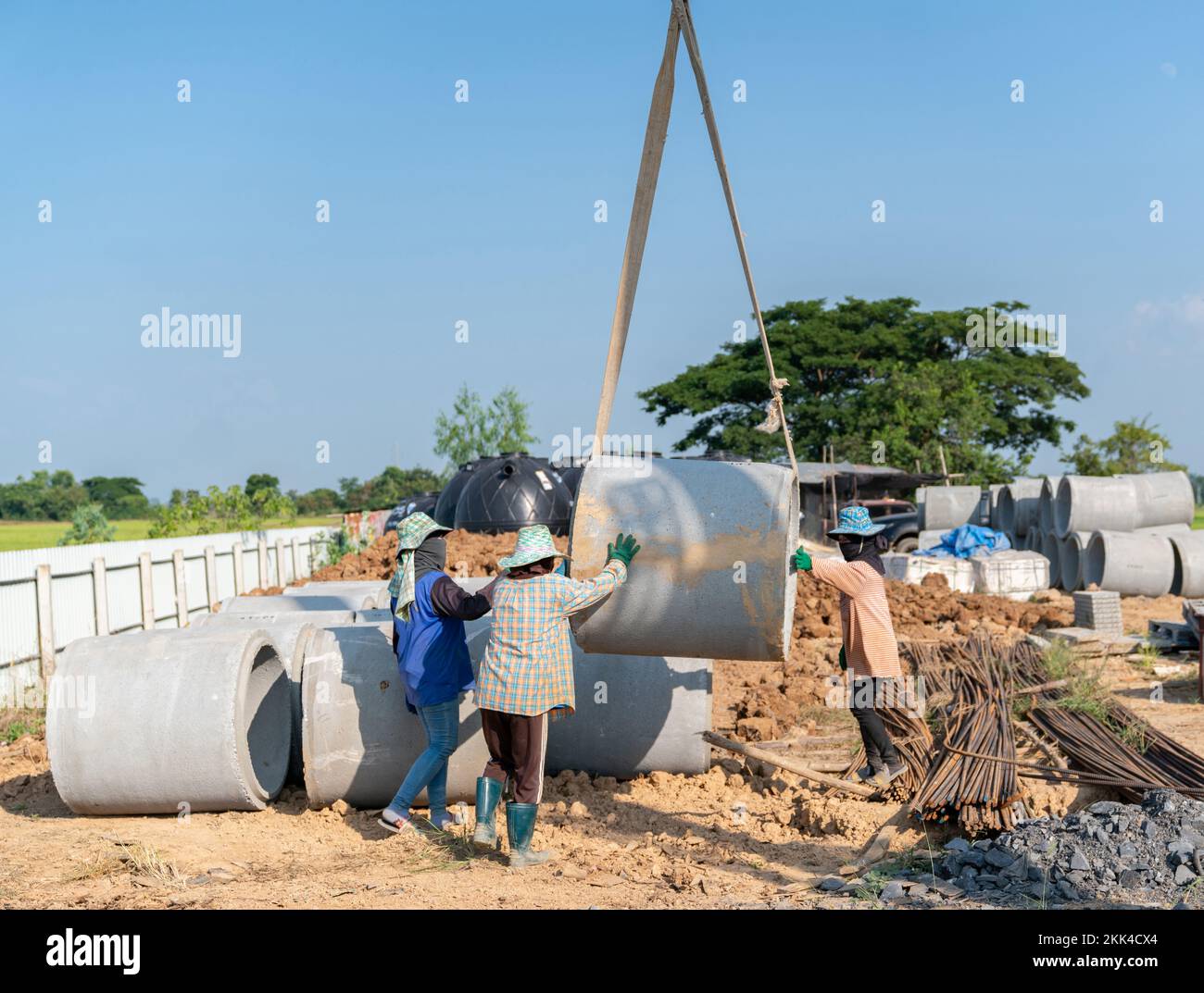 Workers are sorting large concrete pipes at a construction site. Mobile ...