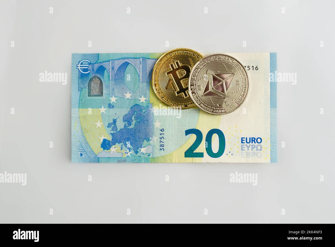 Bitcoin and Ethereum coin over a twenty euro bill over white background ...