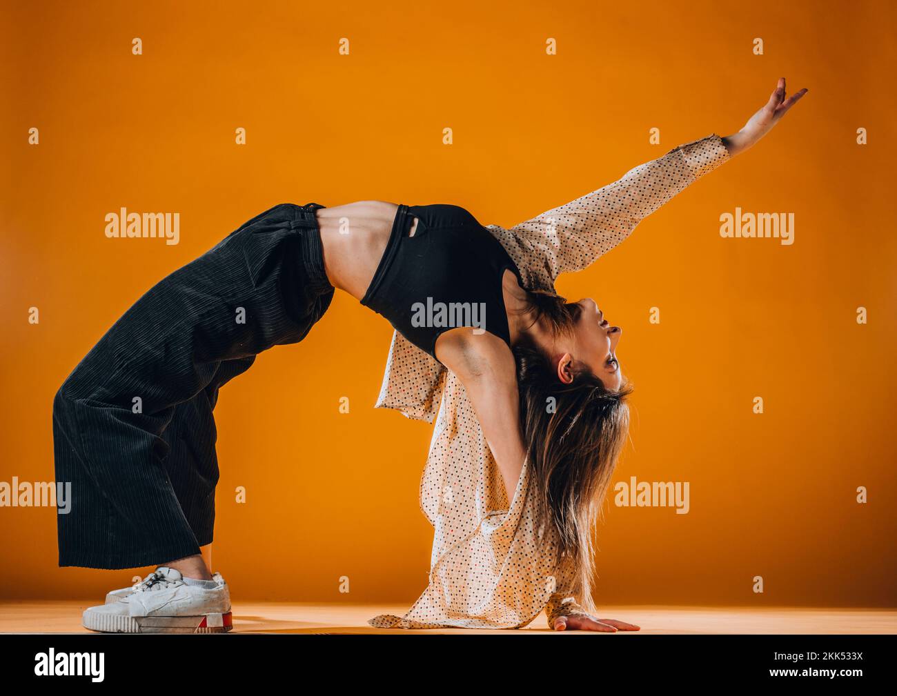 Fit young girl dancer performing a dance routine in the orange studio ...