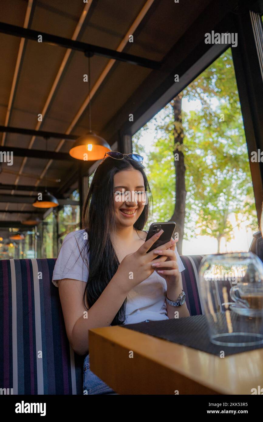 Black haird and beautiful young girl is checking her phone and social ...