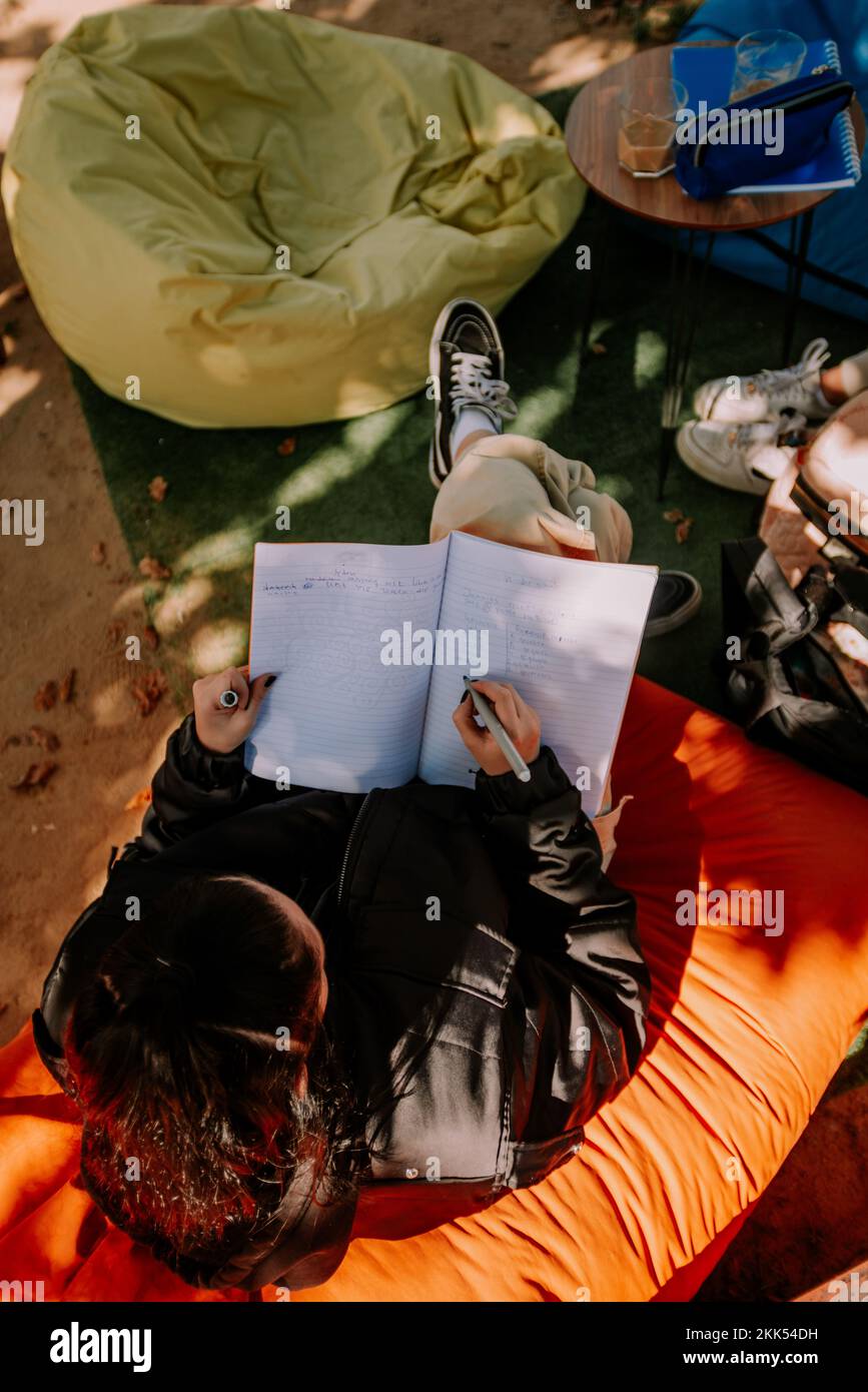 A high school girl with black hair is sitting on a lazy bag and doing ...