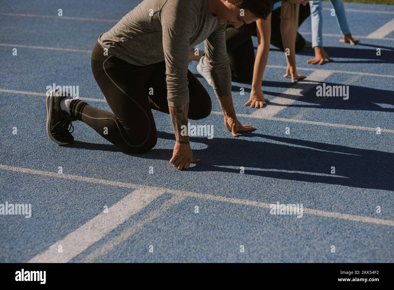 Three sports guys are preparing for running on 100 meters Stock Photo ...