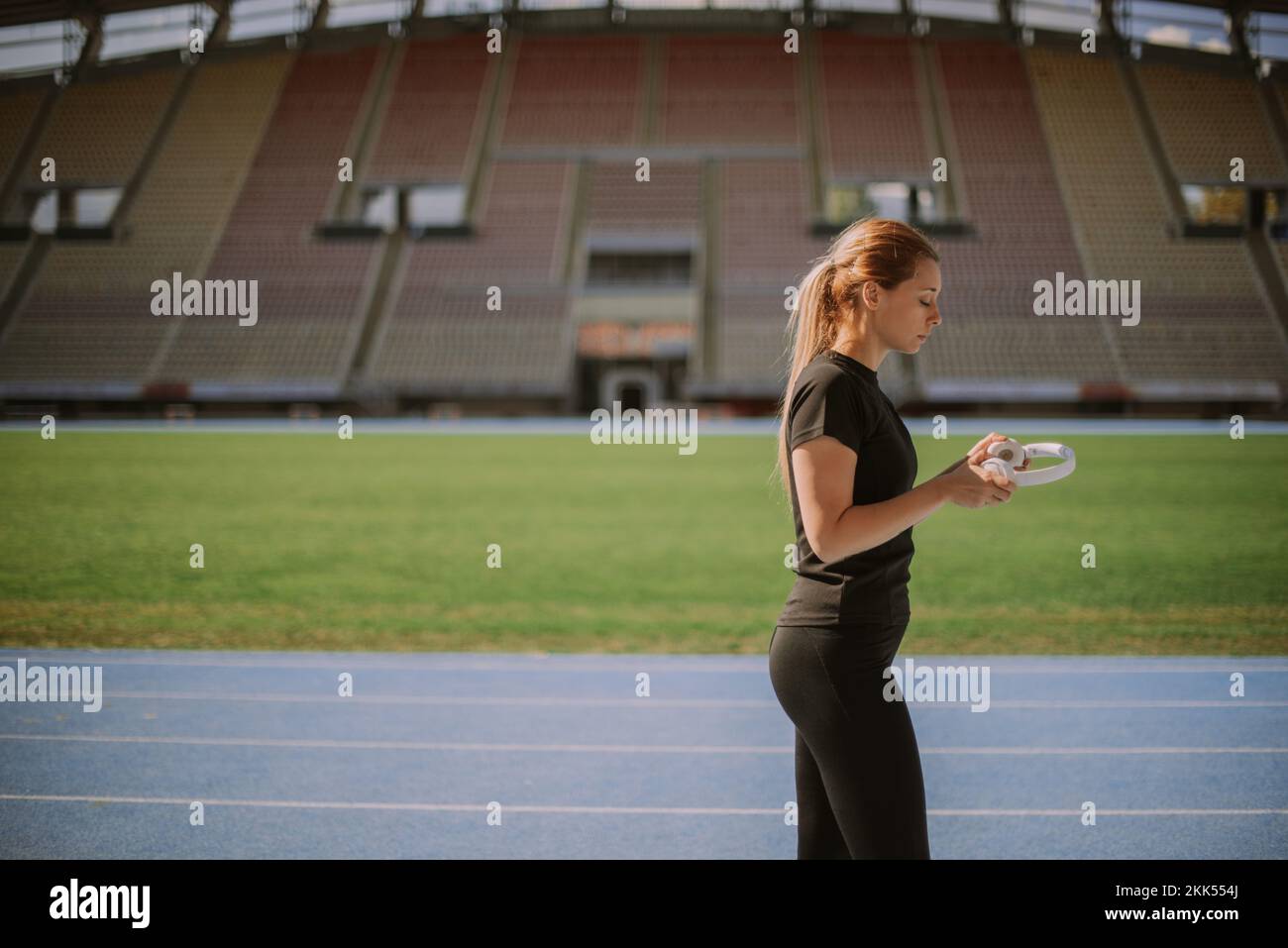 Beautiful female sportsperson is about to run on a stadium's track. She ...