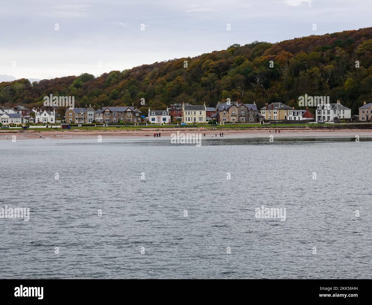 People walking, digging, on the beach at the city of Millport, the only ...