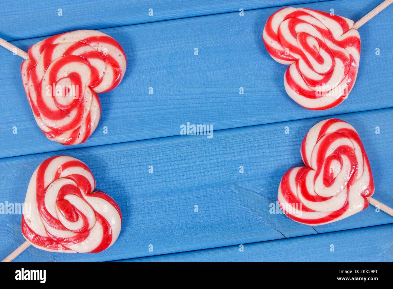 Sweet colorful funny lollipop in shape of heart on blue boards ...