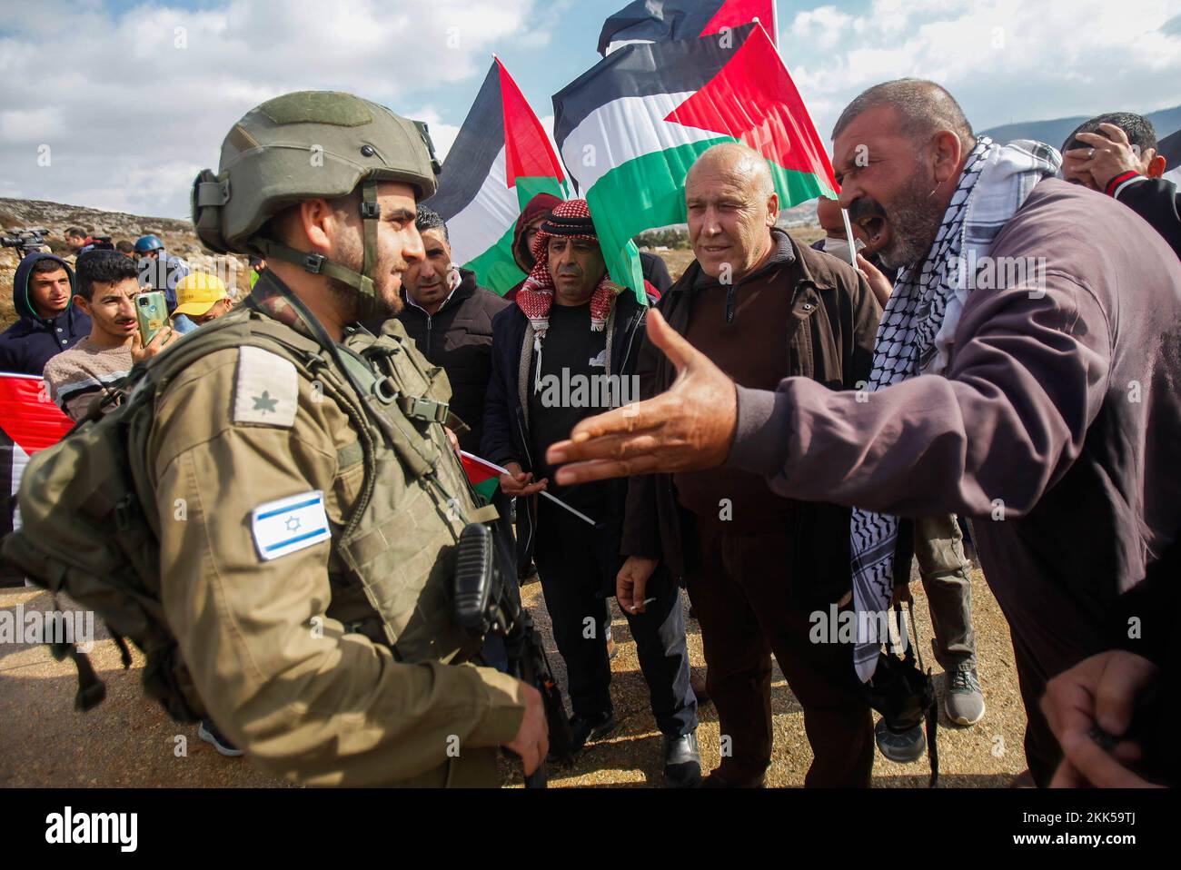 A Palestinian protester holding a flag argues with the Israeli soldier ...