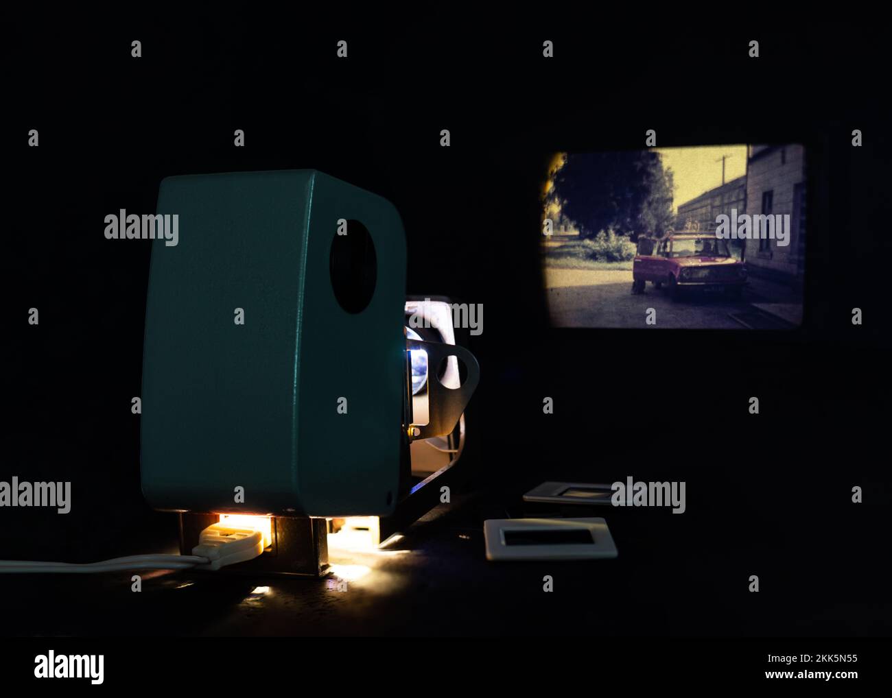 Vintage green -blue slide projector shows blured old slide on dark ...