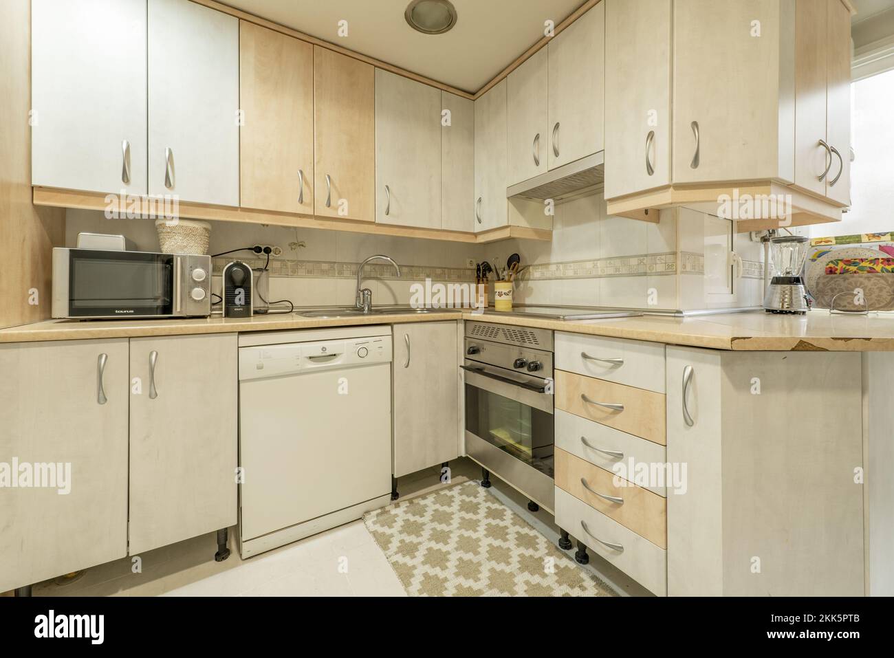 Corner of a kitchen covered with white furniture combined with wood ...
