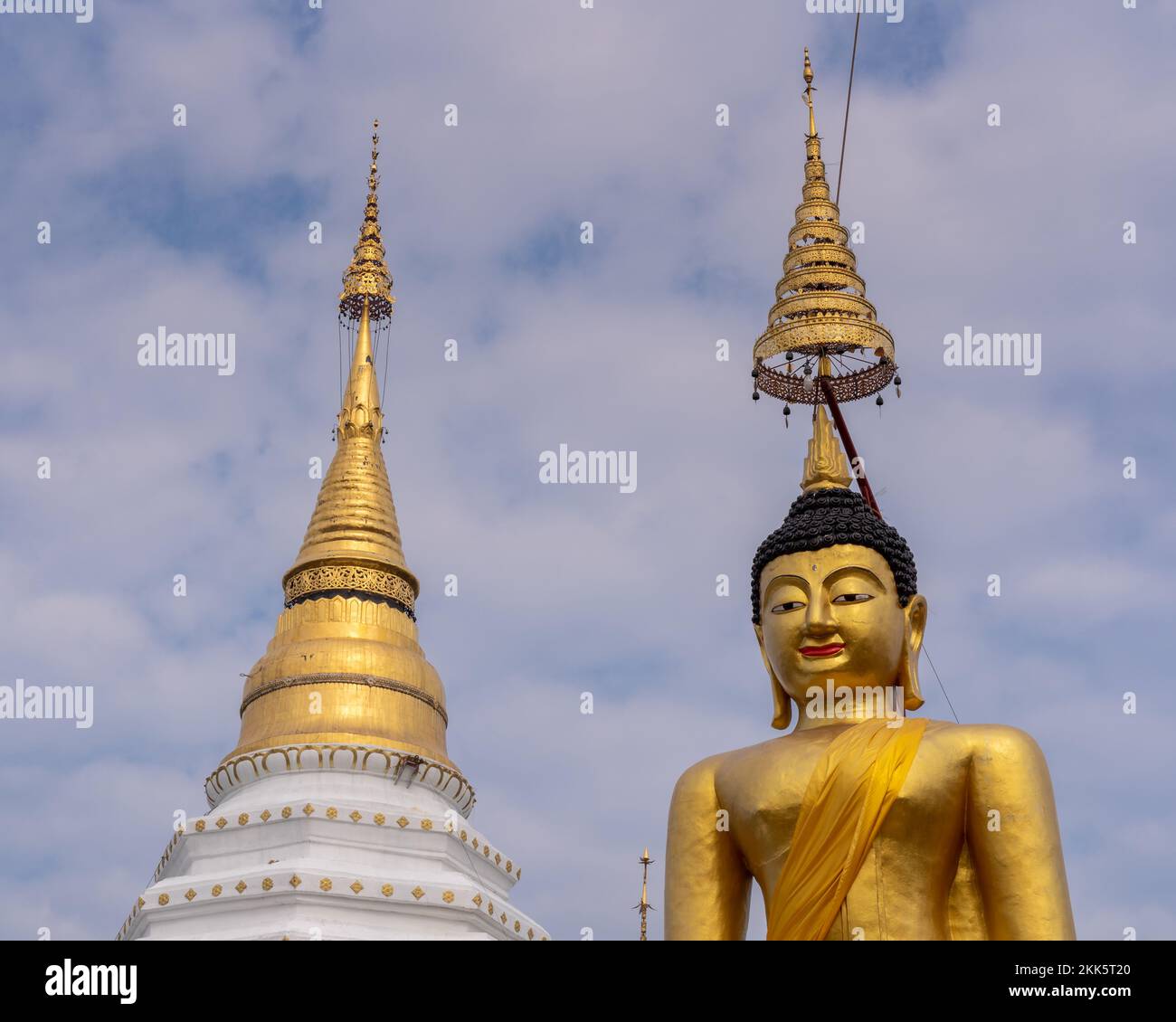 Low angle view of golden buddha statue and ancient stupa on blue sky ...