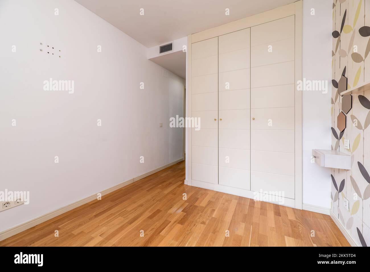 Bedroom with a built-in wardrobe with three white wooden doors, papered ...