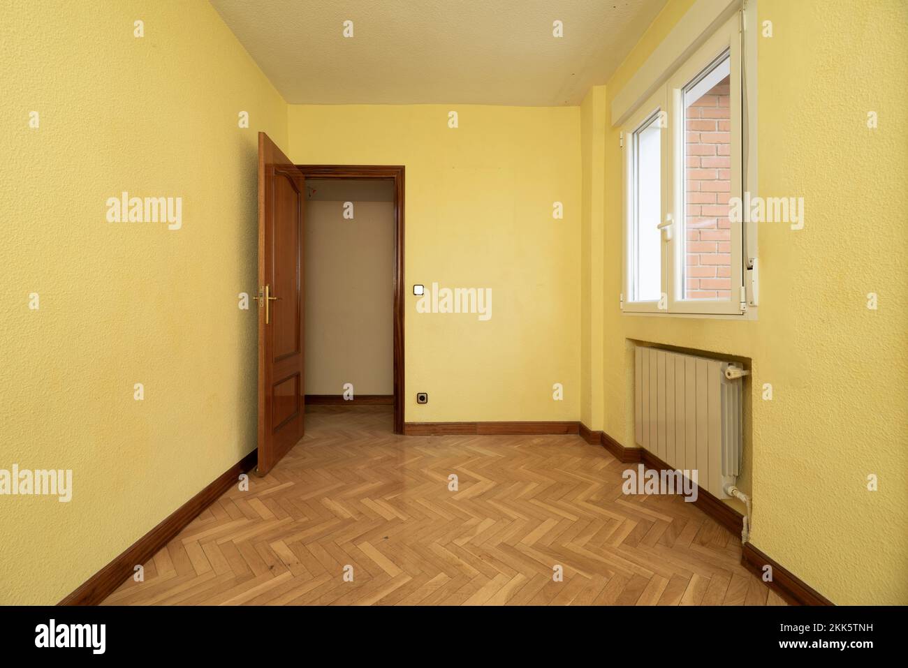 Small empty room with herringbone parquet flooring, niche under window ...