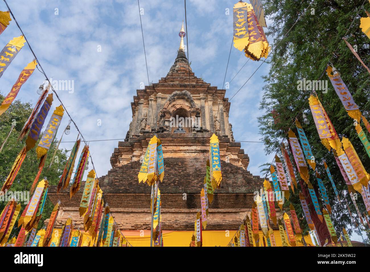 View of ancient brick and stucco stupa or chedi with colorful banners ...