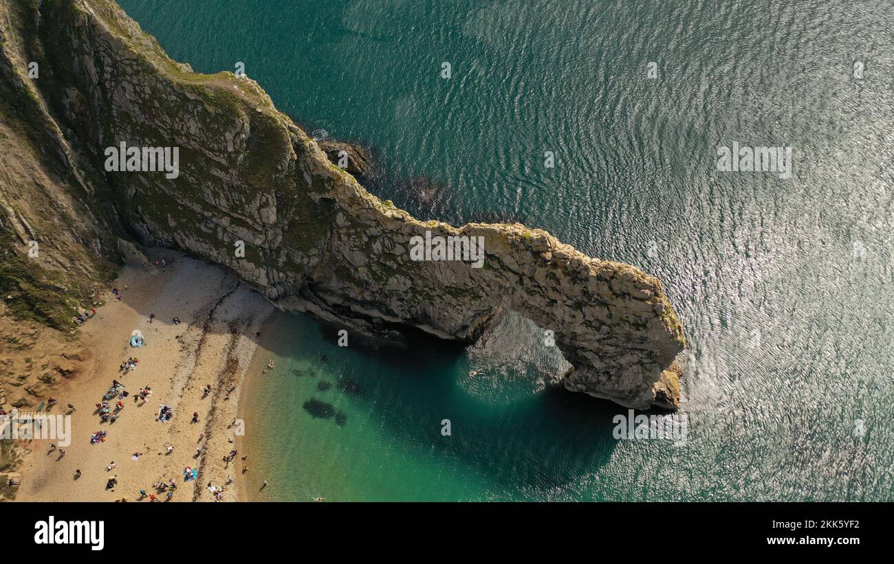 An aerial drone view of Durdle Door limestone arch and a sandy beach on ...
