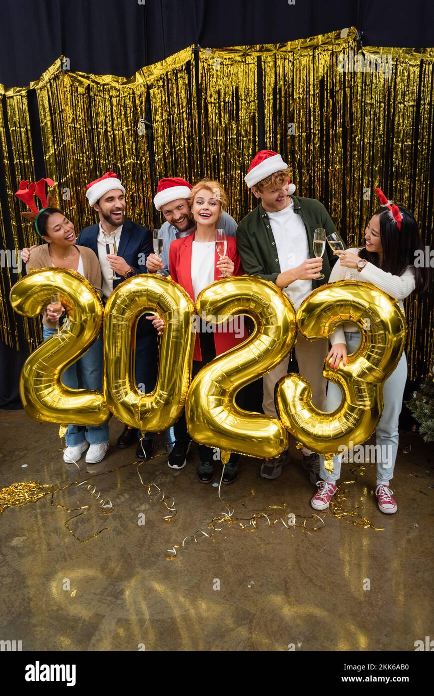 Interracial business people holding glasses of champagne near balloons ...