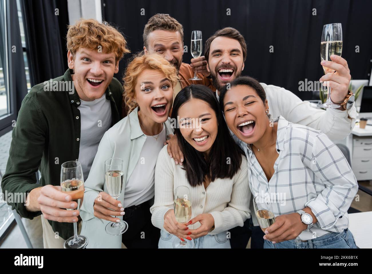 Cheerful interracial business people holding glasses of champagne and ...