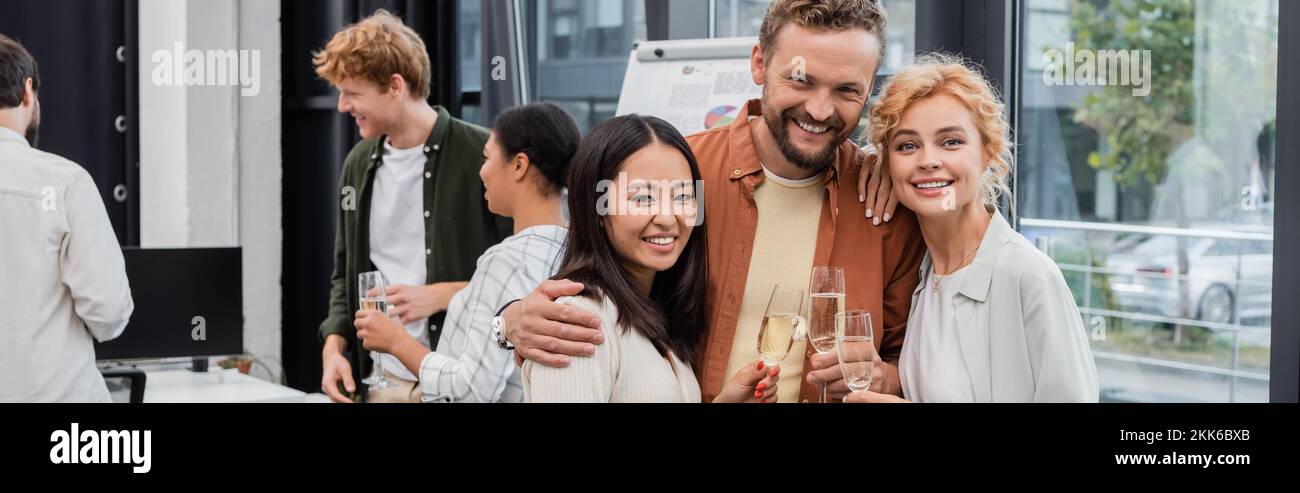 Interracial business people hugging and holding glasses of champagne in ...