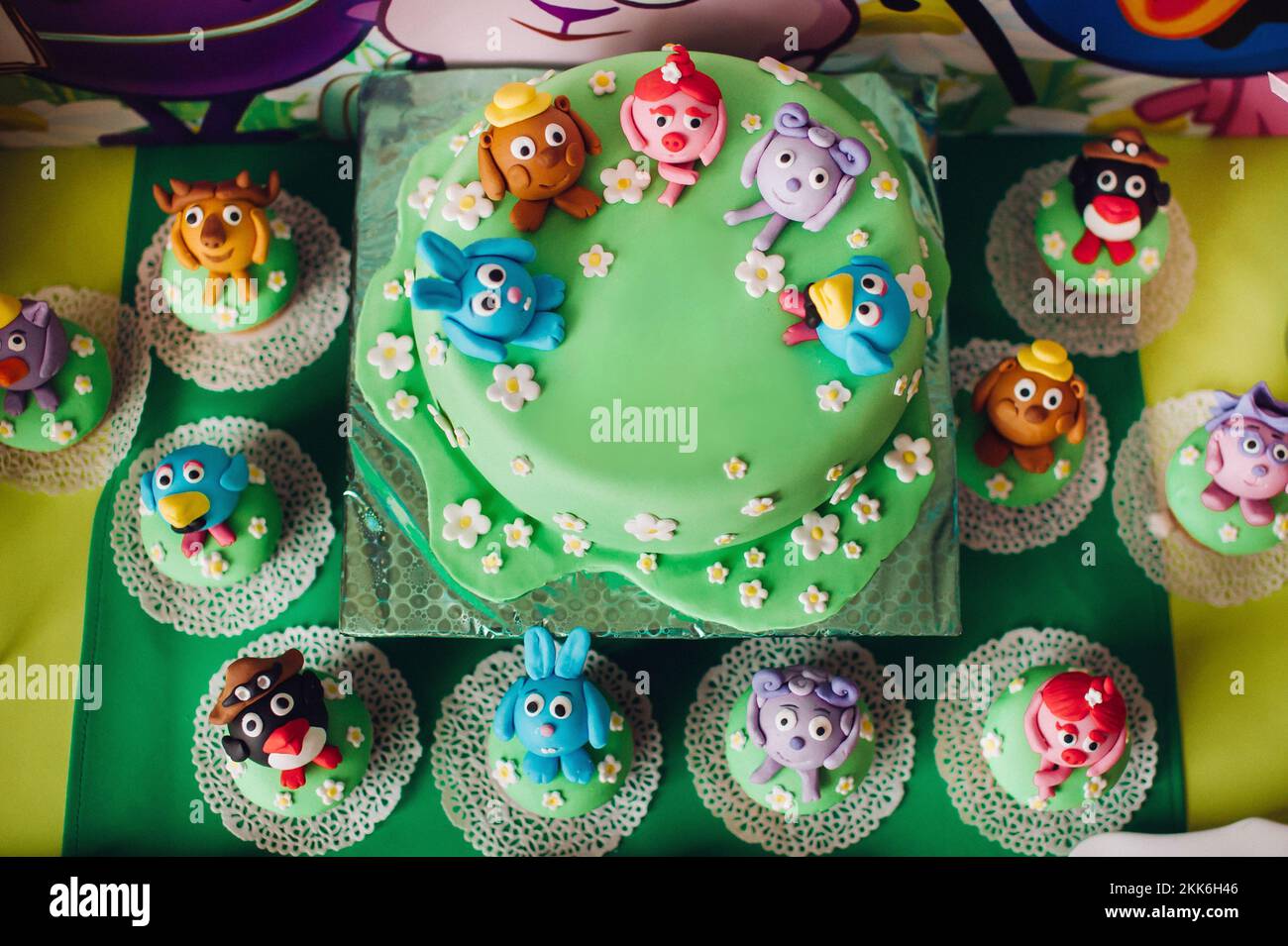 festive children's table with a beautiful cake decorated with green and ...