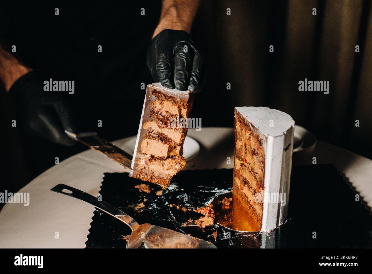 Amazing Cakes. A black-gloved chef is slicing a chocolate wedding cake ...