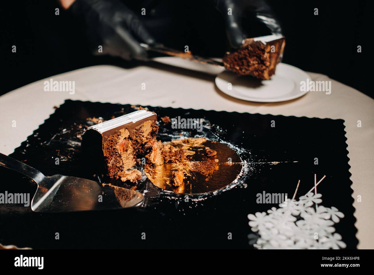 Amazing Cakes. A black-gloved chef is slicing a chocolate wedding cake ...