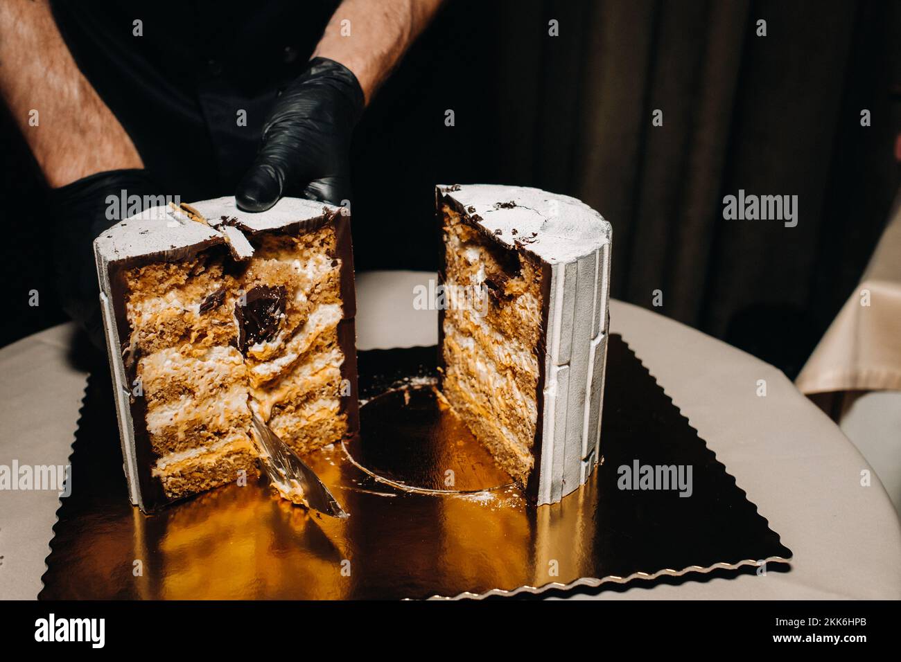 Amazing Cakes. A black-gloved chef is slicing a chocolate wedding cake ...