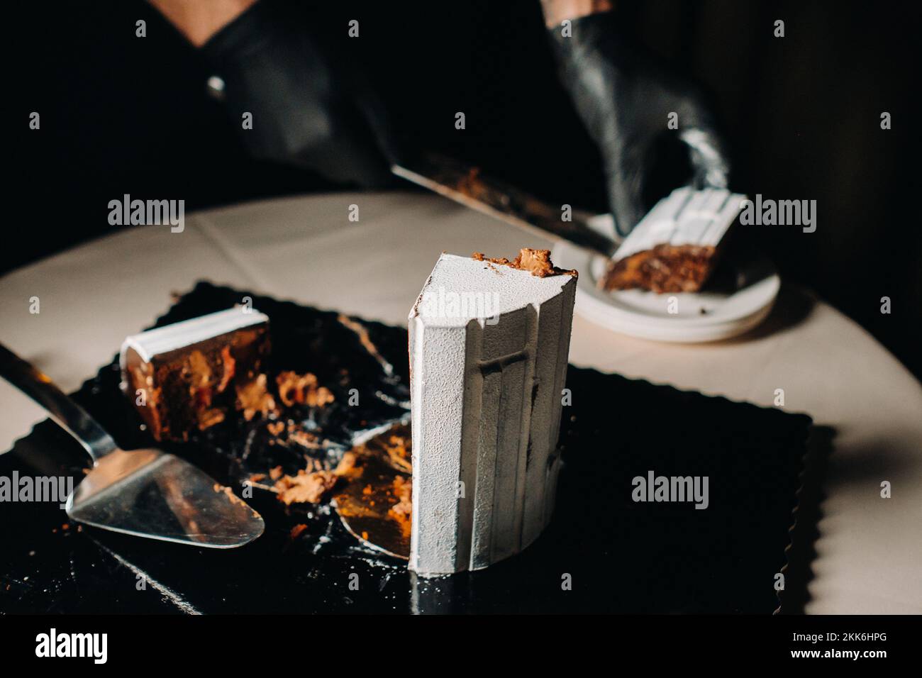 Amazing Cakes. A black-gloved chef is slicing a chocolate wedding cake ...