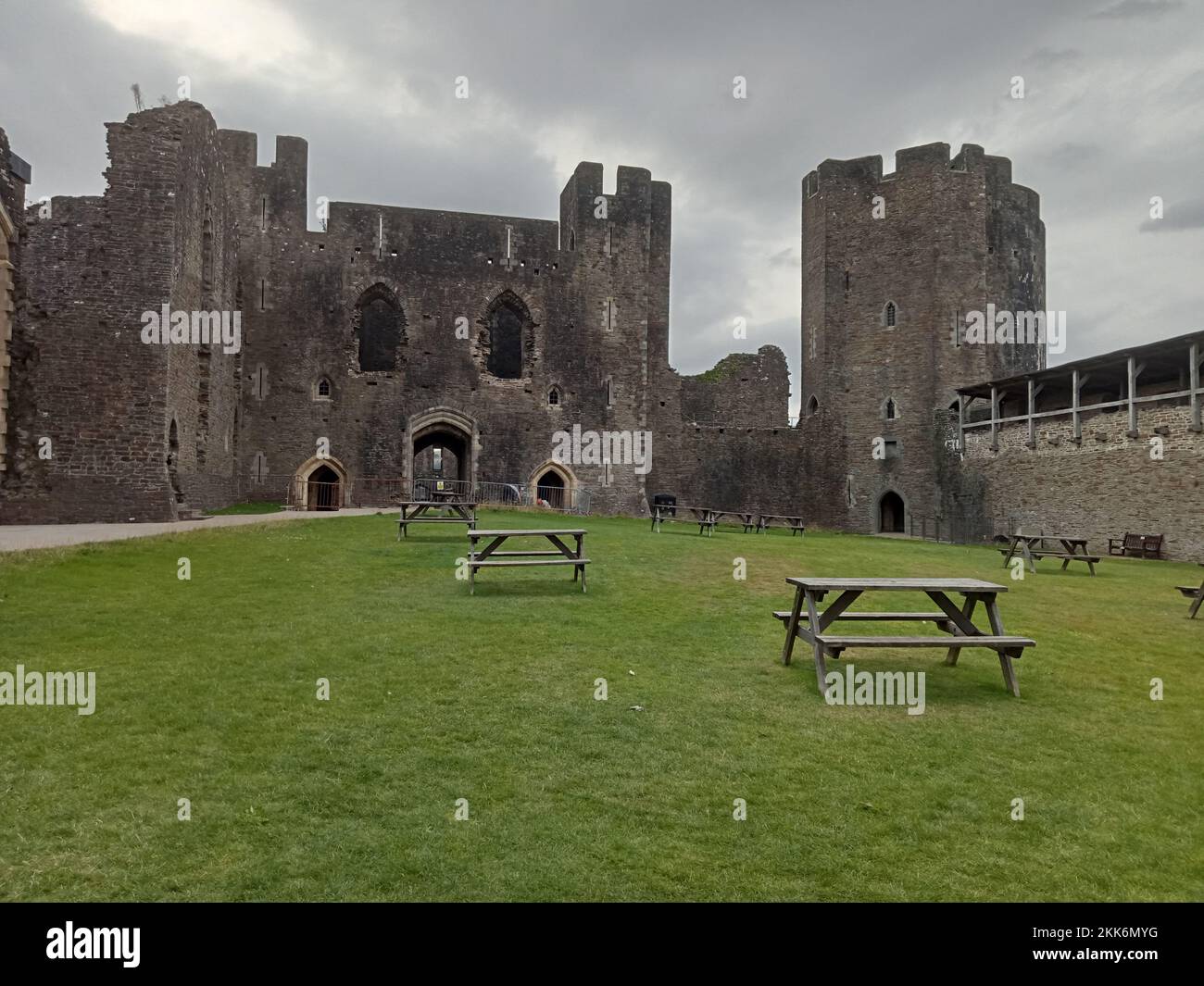 The exterior of Caerphilly Castle with benches on the grass of the yard ...