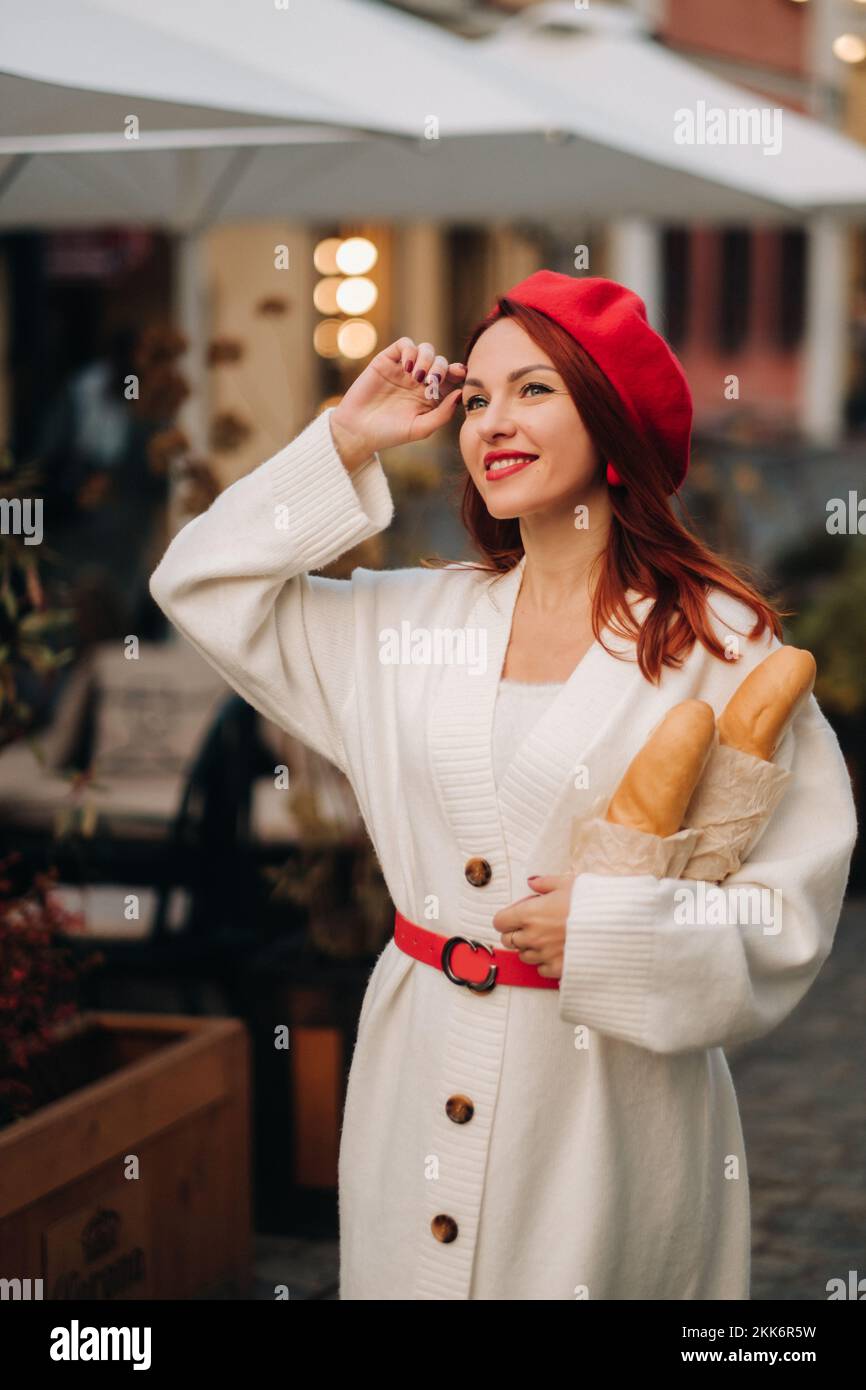 Portrait of a pretty woman in a red beret and a white cardigan with ...