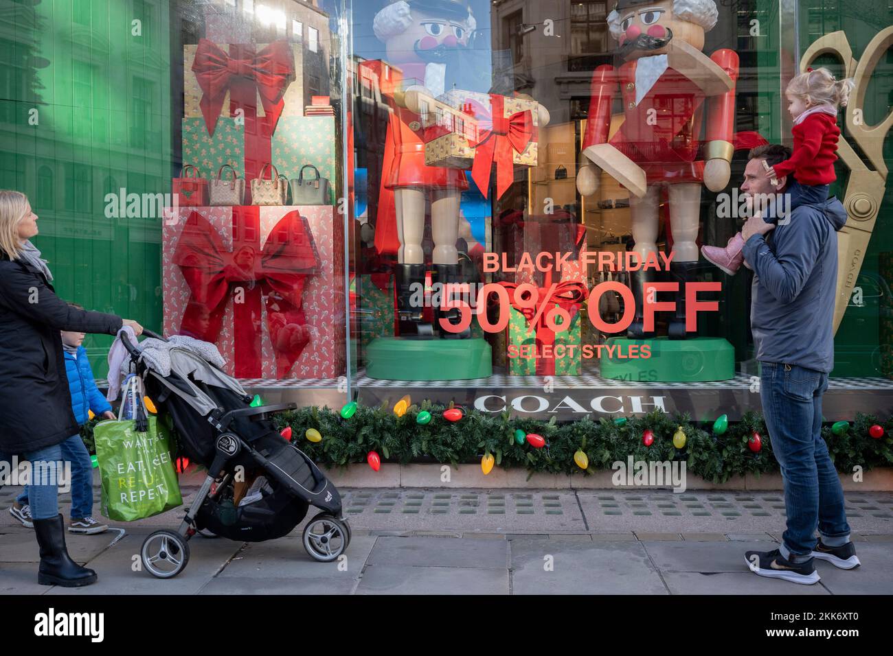 Shoppers walk past a Christmas window display that promotes Black ...