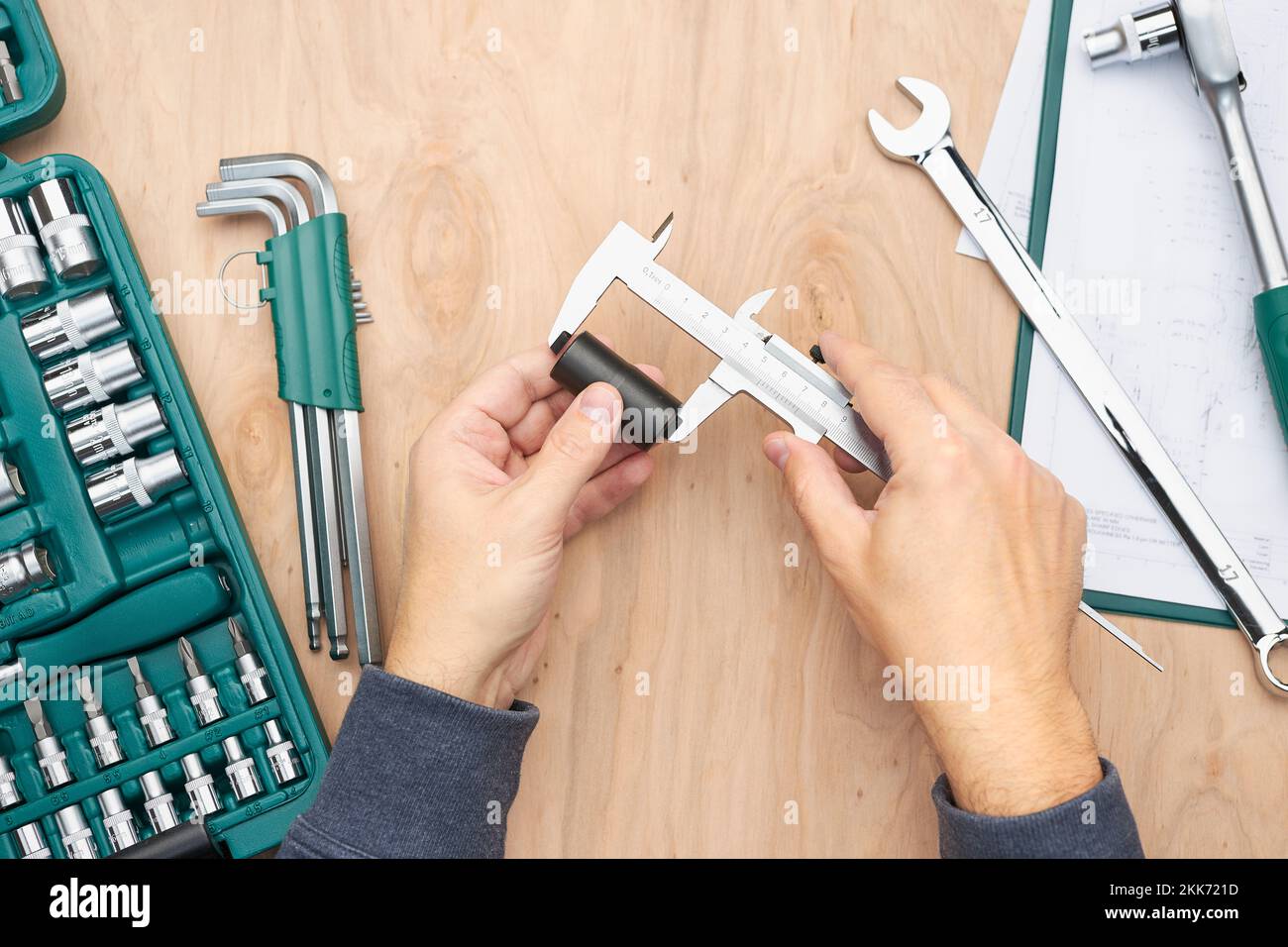 Man measuring object using calliper. Workshop table with many tools ...