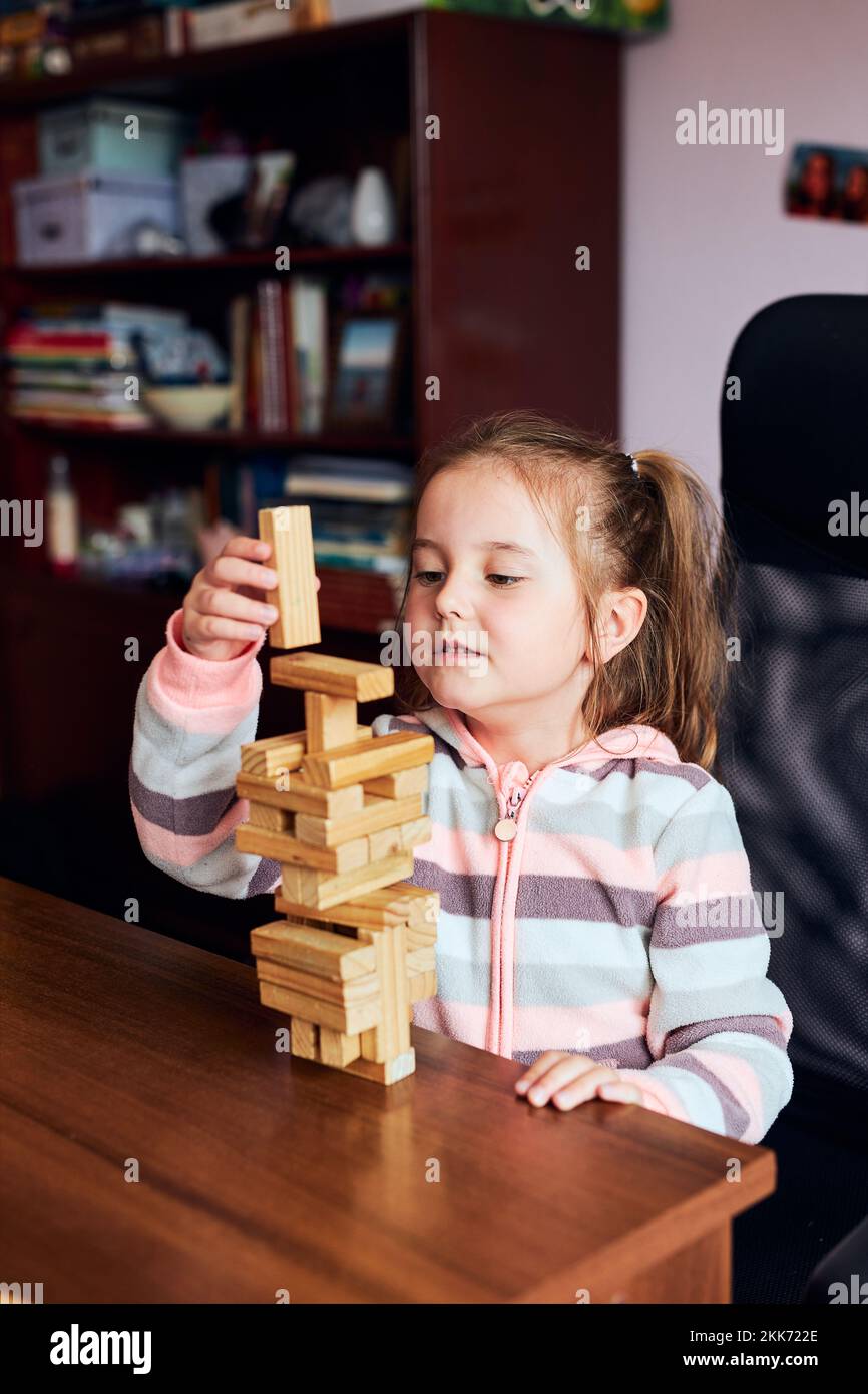 Little girl preschooler playing with wooden blocks toy building a tower ...