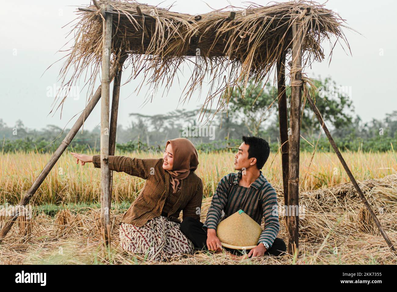 A couple of asian boy and girl sitting in a hut in traditional Javanese ...