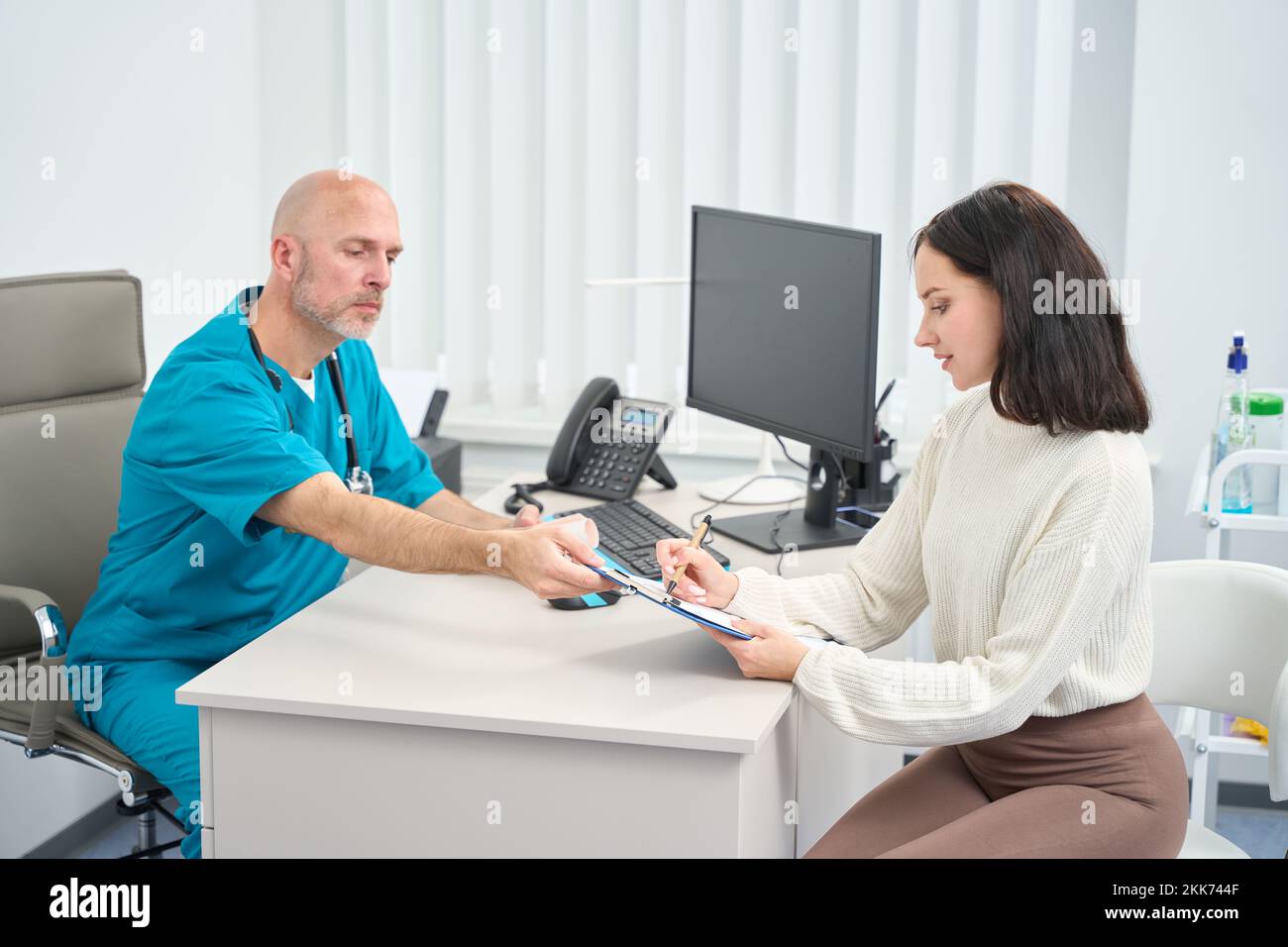 Patient is signing official documents at appointment with a doctor ...