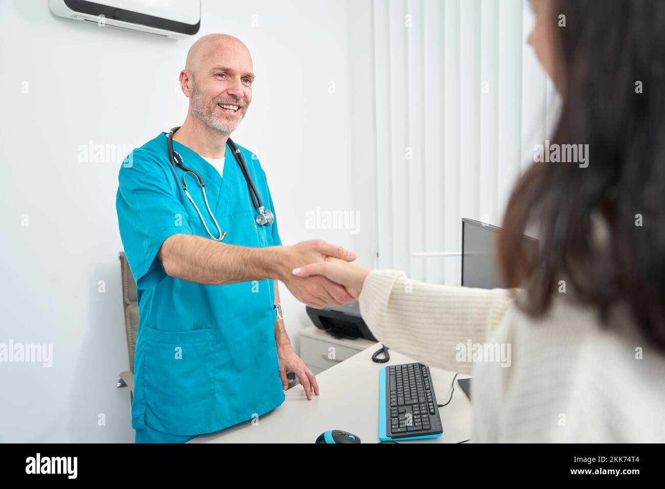 Doctor shakes hands with the patient from behind the desktop Stock ...