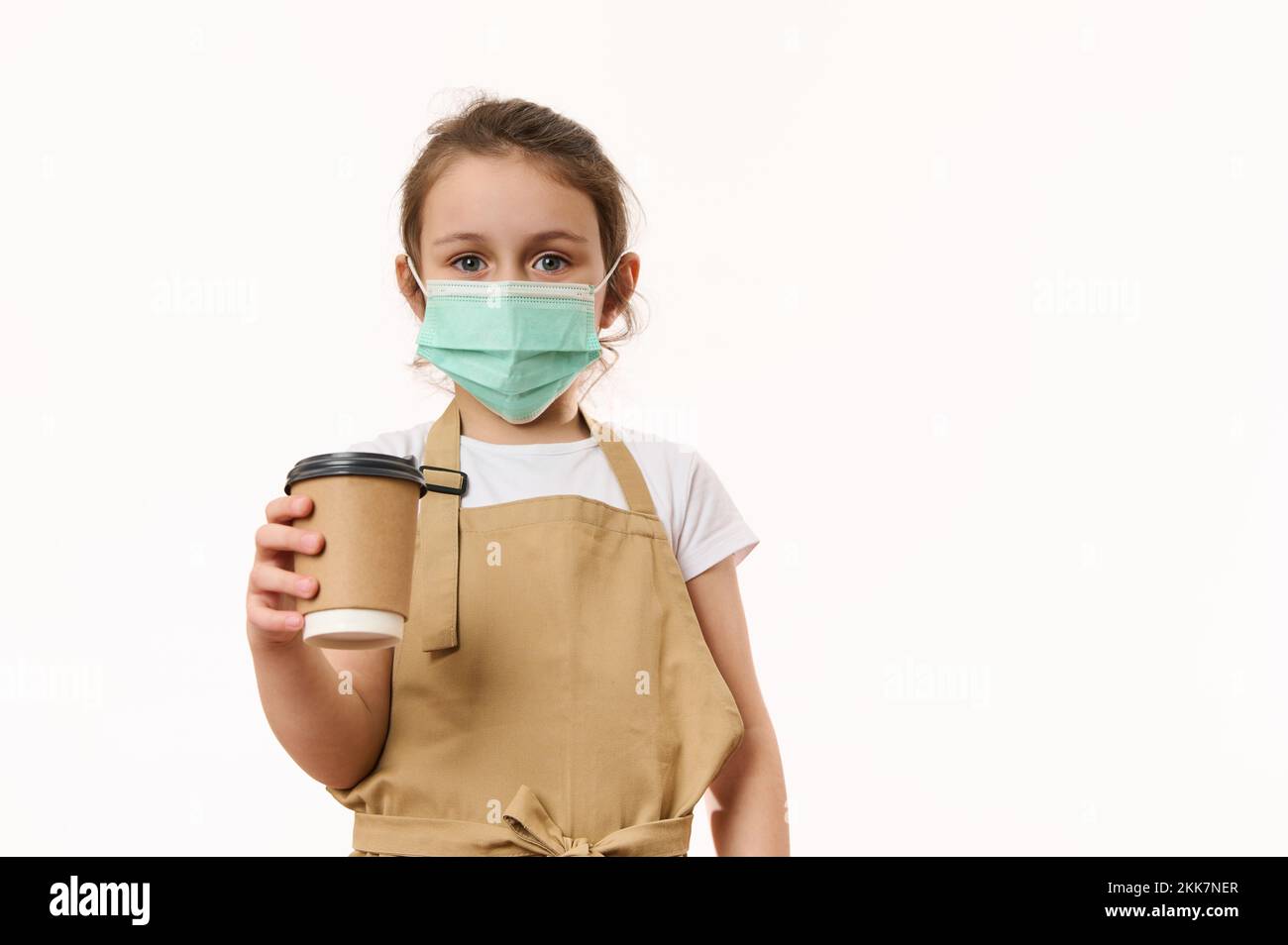 Little child girl dressesd as barista in chef apron, handing out a ...