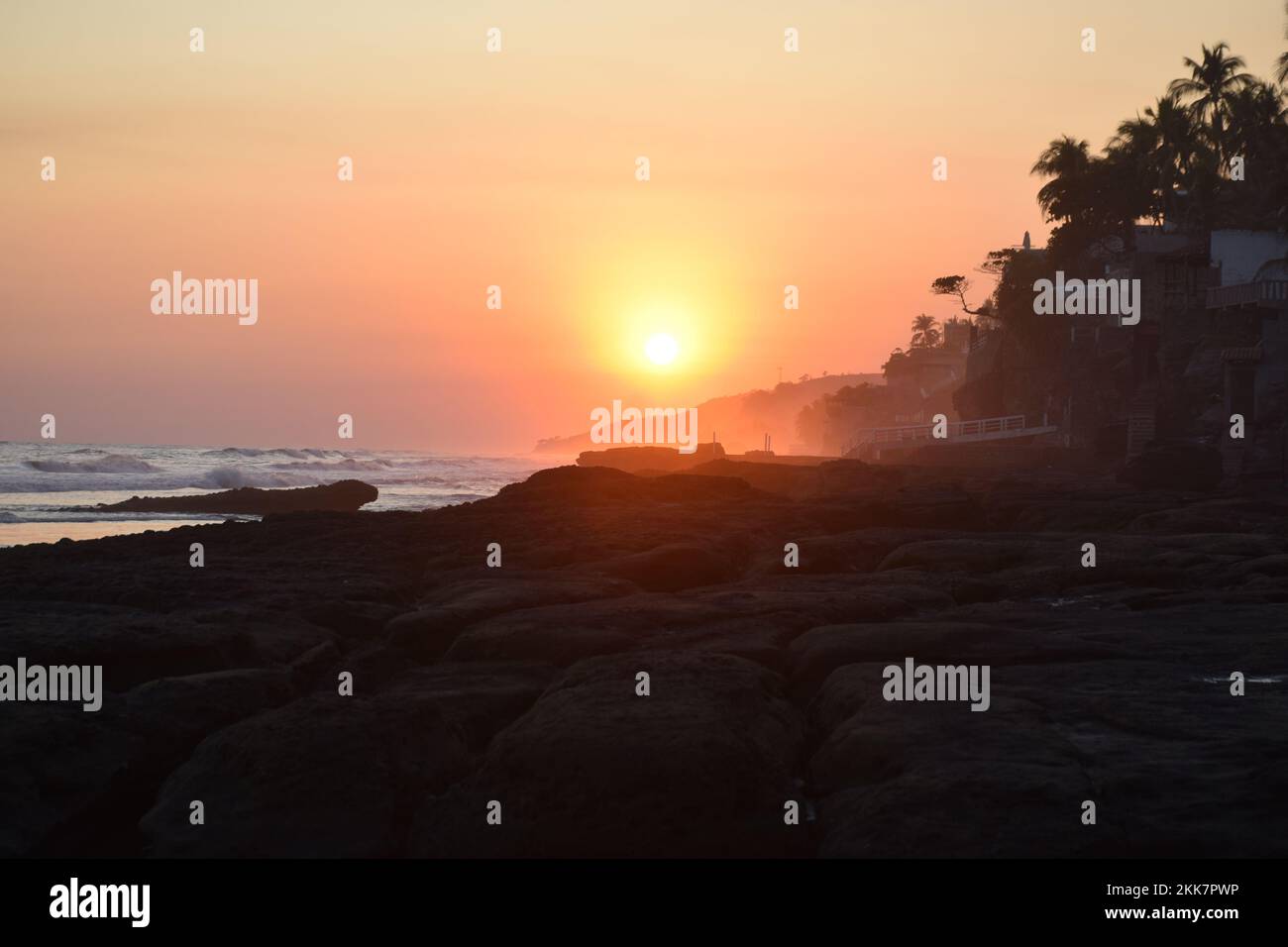 A low-angle of sunset over seascape a red sun in the horizon sky ...