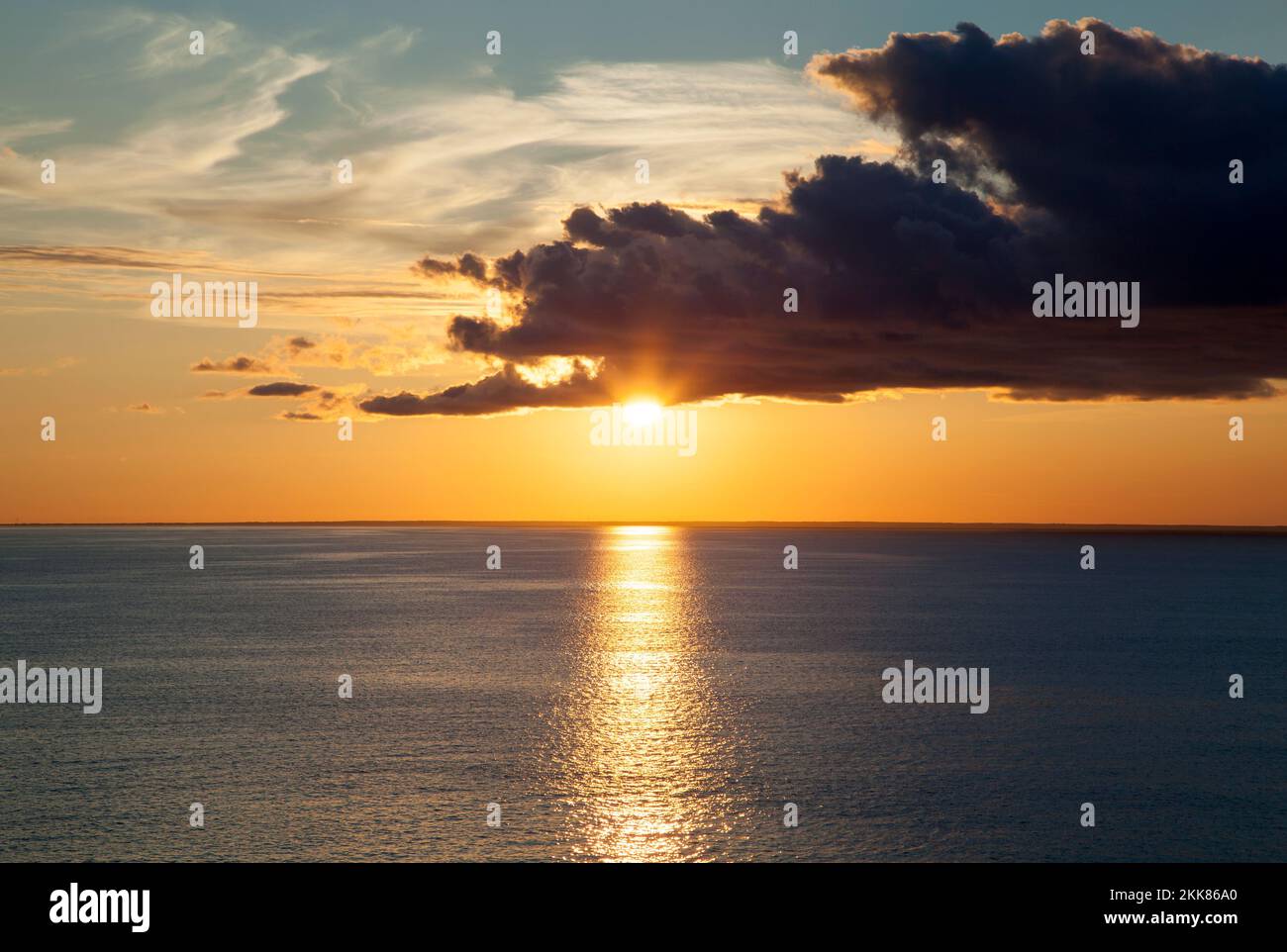 The sunset view of a sun half hidden behind the dark cloud over Gulf of ...
