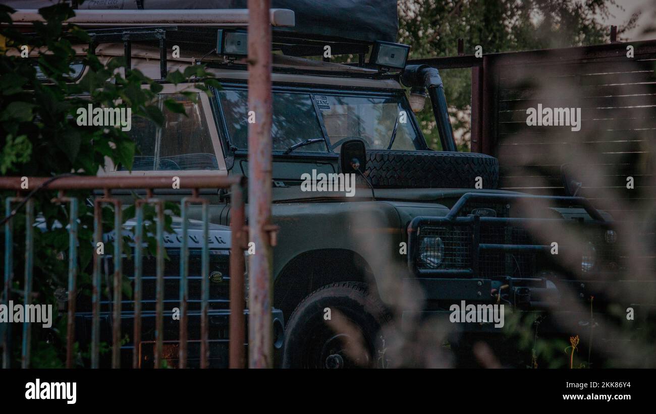 An army green Land Rover behind a rusty fence in a rural area Stock ...