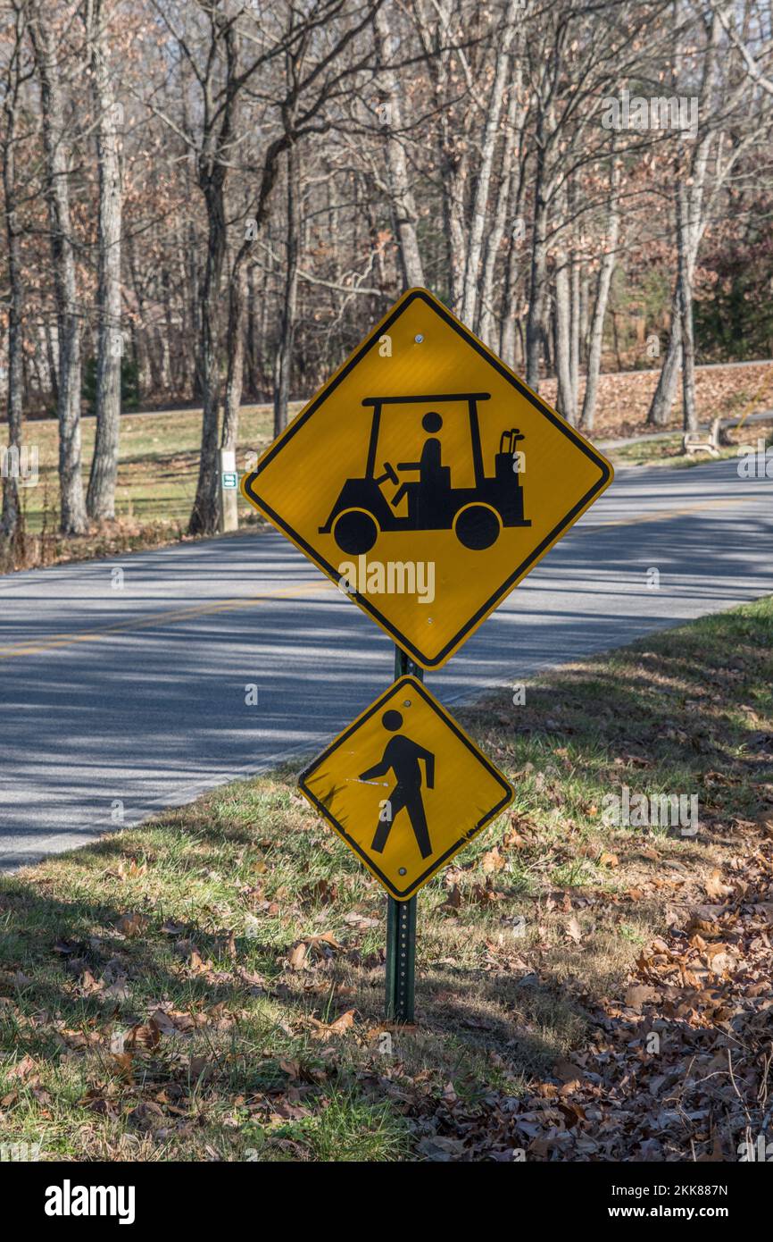 Two signs on a pole alongside the street by a golf course and trails ...