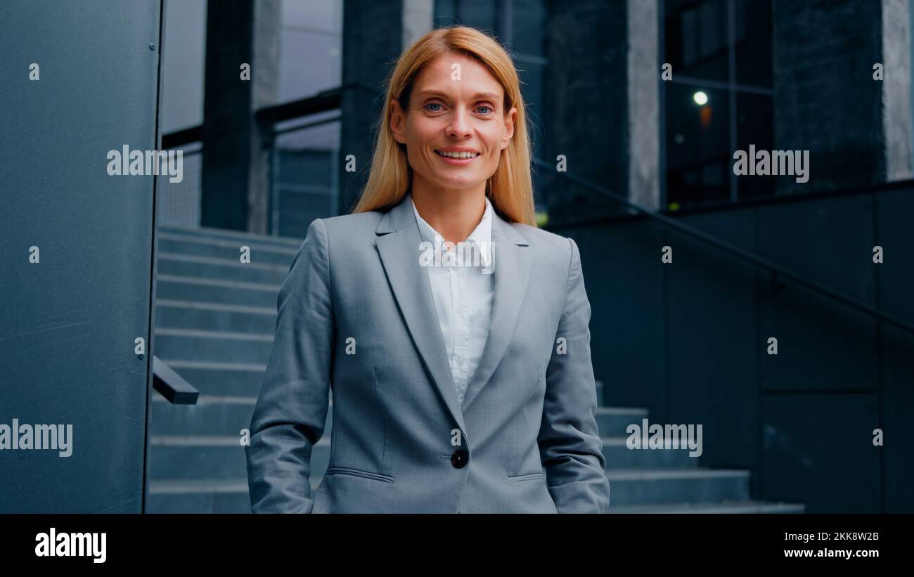Dreamy business lady standing near office building looking to side ...