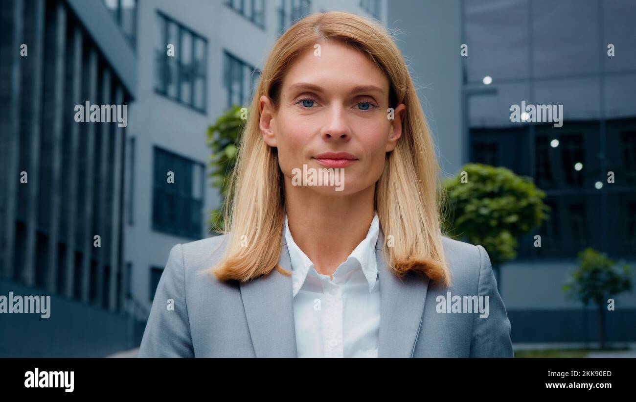 Close-up young smiling businesswoman in suit standing outdoors against ...