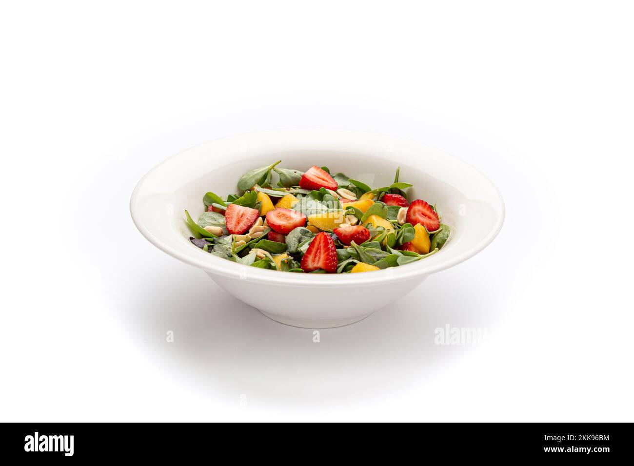 A colorful fruit salad made of strawberries, peaches and green leaves ...