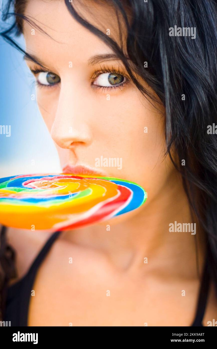 Beautiful Bikini Female With Stunning Hazel Eyes With Surprised Expression Sucking On A Rainbow