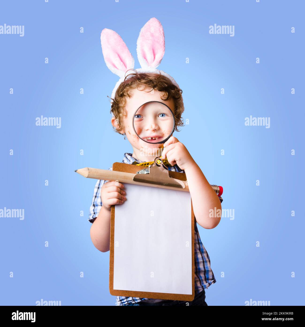 Delightful young boy wearing bunny ears looking through magnifying ...
