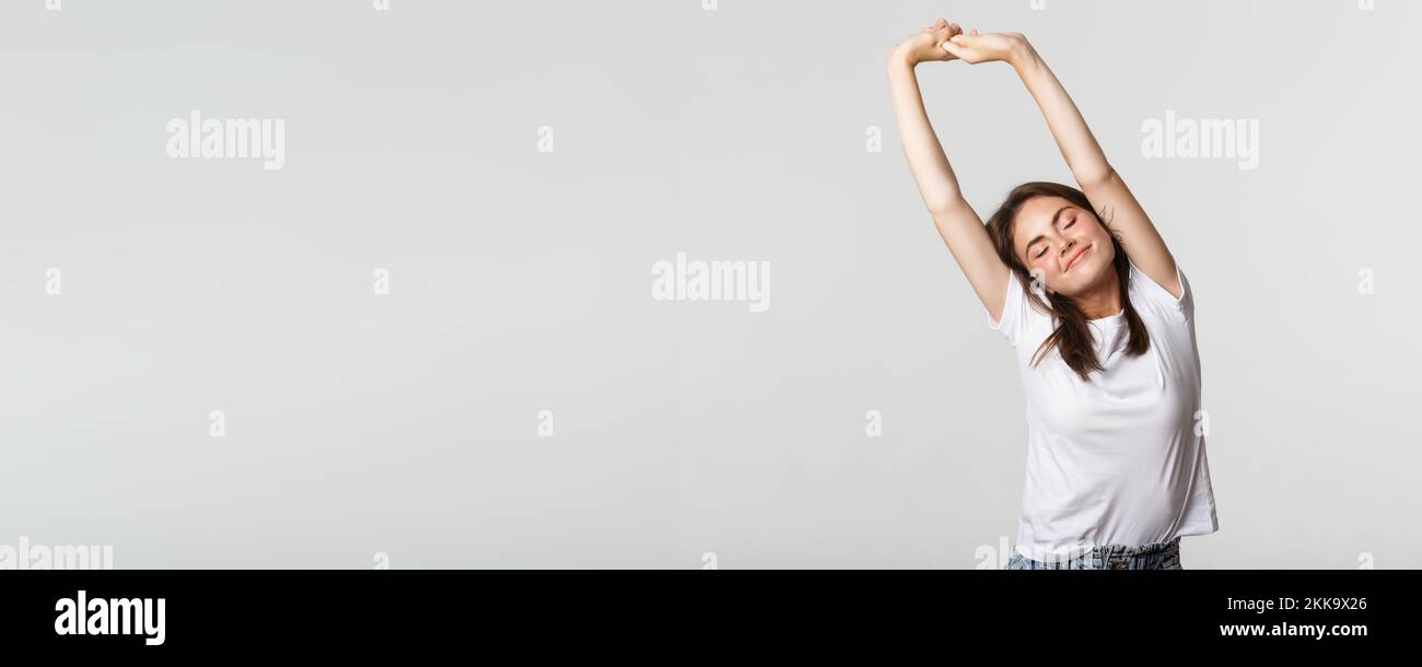 Portrait of relaxed carefree brunette girl stretching with satisfied ...