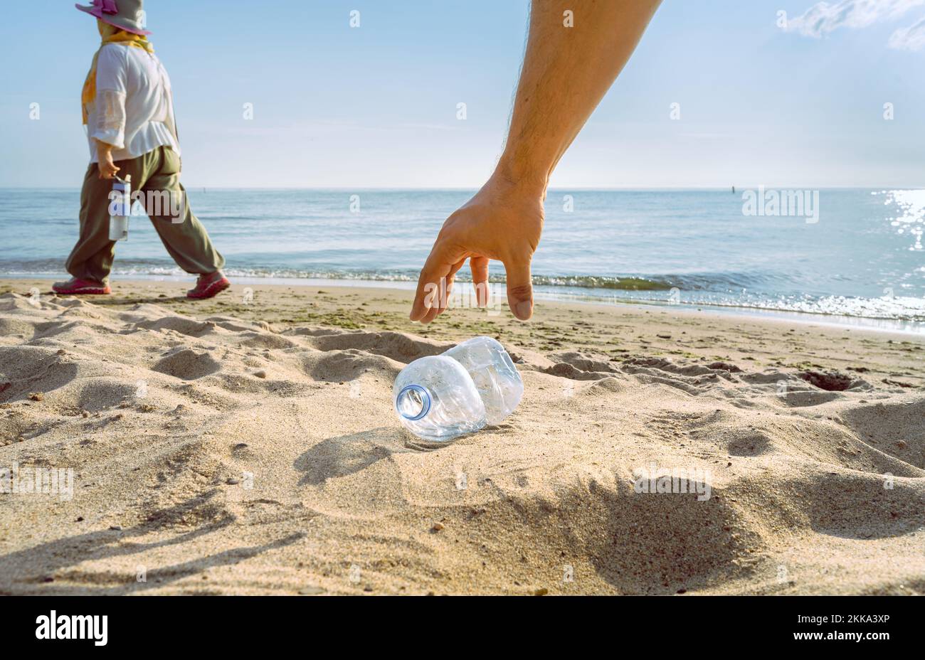 A hand reaches to pick up an empty plastic bottle Stock Photo - Alamy