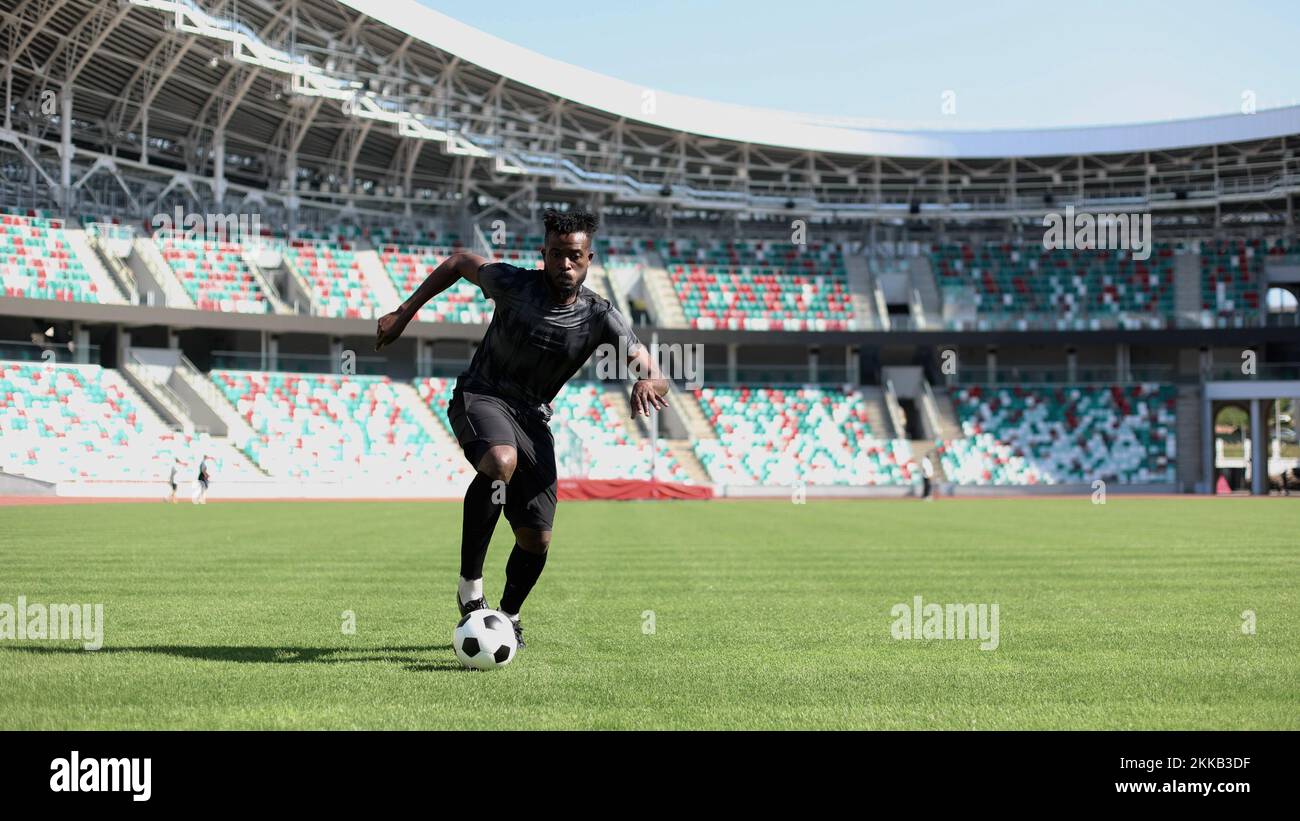African American man playing football on the stadium field. A man runs ...