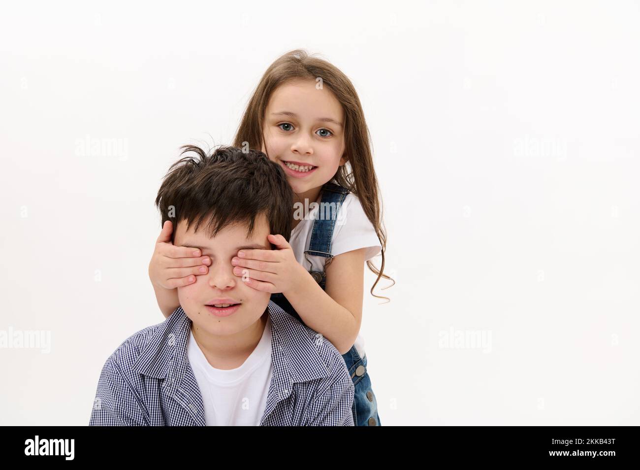 Adorable little child girl closing her brother's eyes with her hands ...