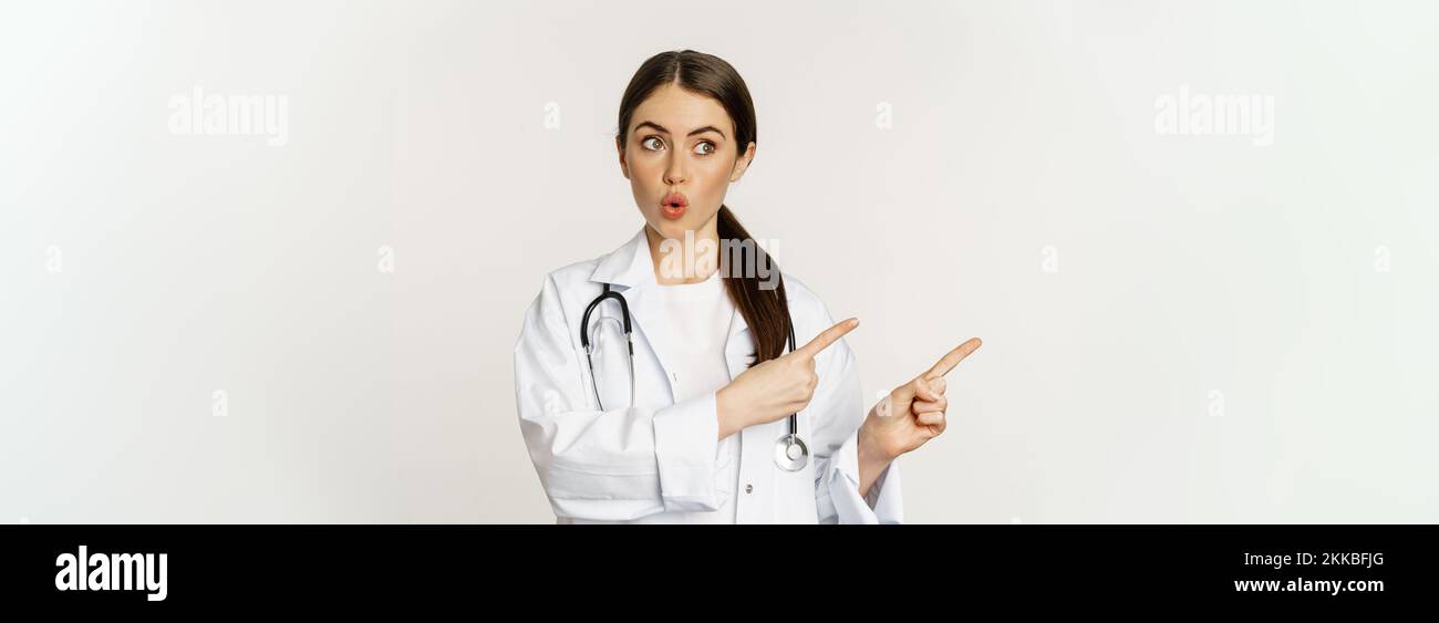 Surprised doctor, physician pointing fingers left and looking at logo ...